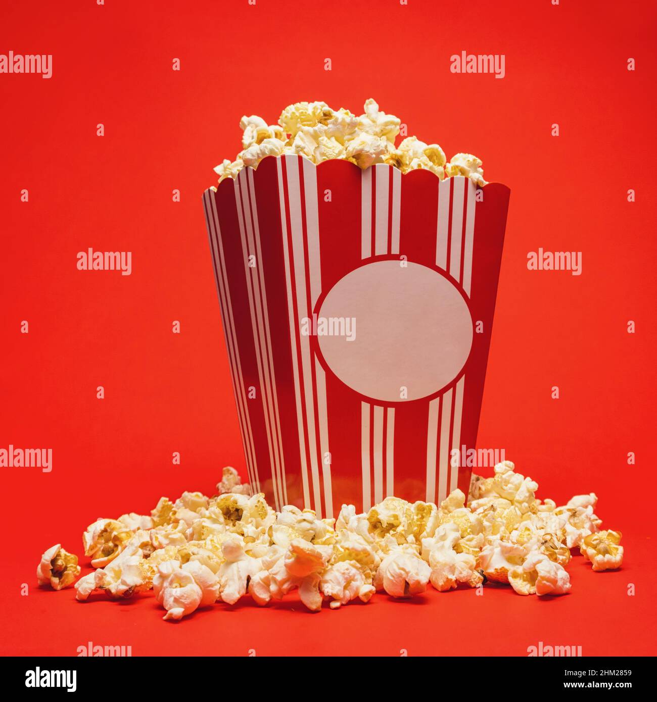 Popcorn in a large square box and around on a bright red background ...