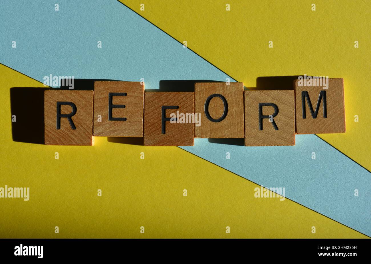 Reform, word in wooden alphabet letters isolated on blue and yellow ...