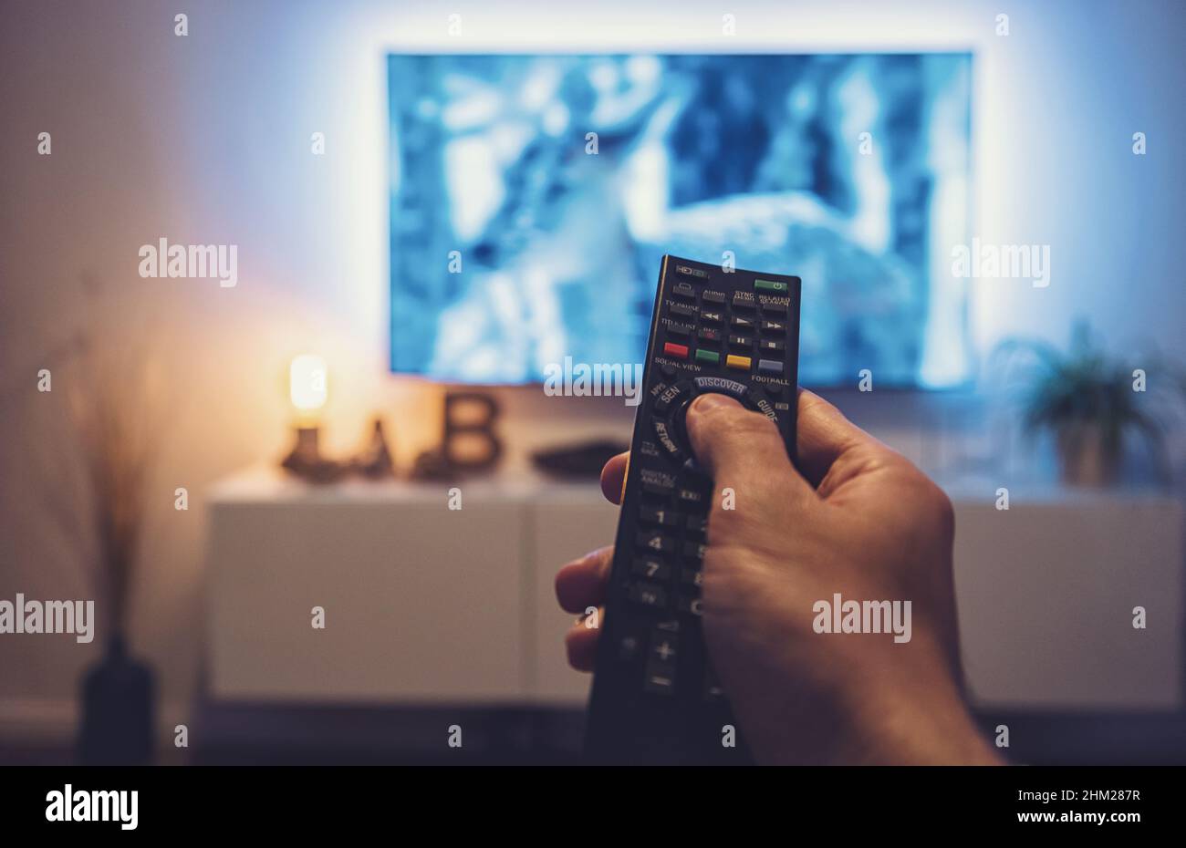 man Watching movie and using remote control Stock Photo - Alamy