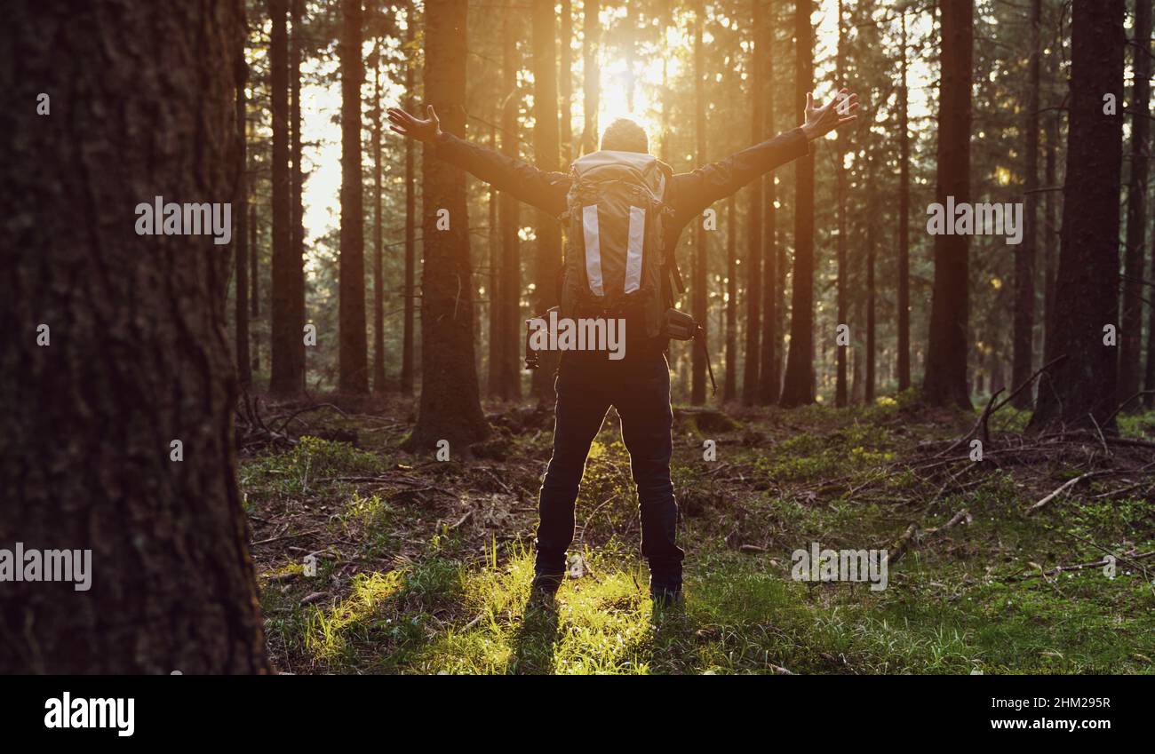 Man Traveler relaxing alone in the forest at sunset with hands raised ...