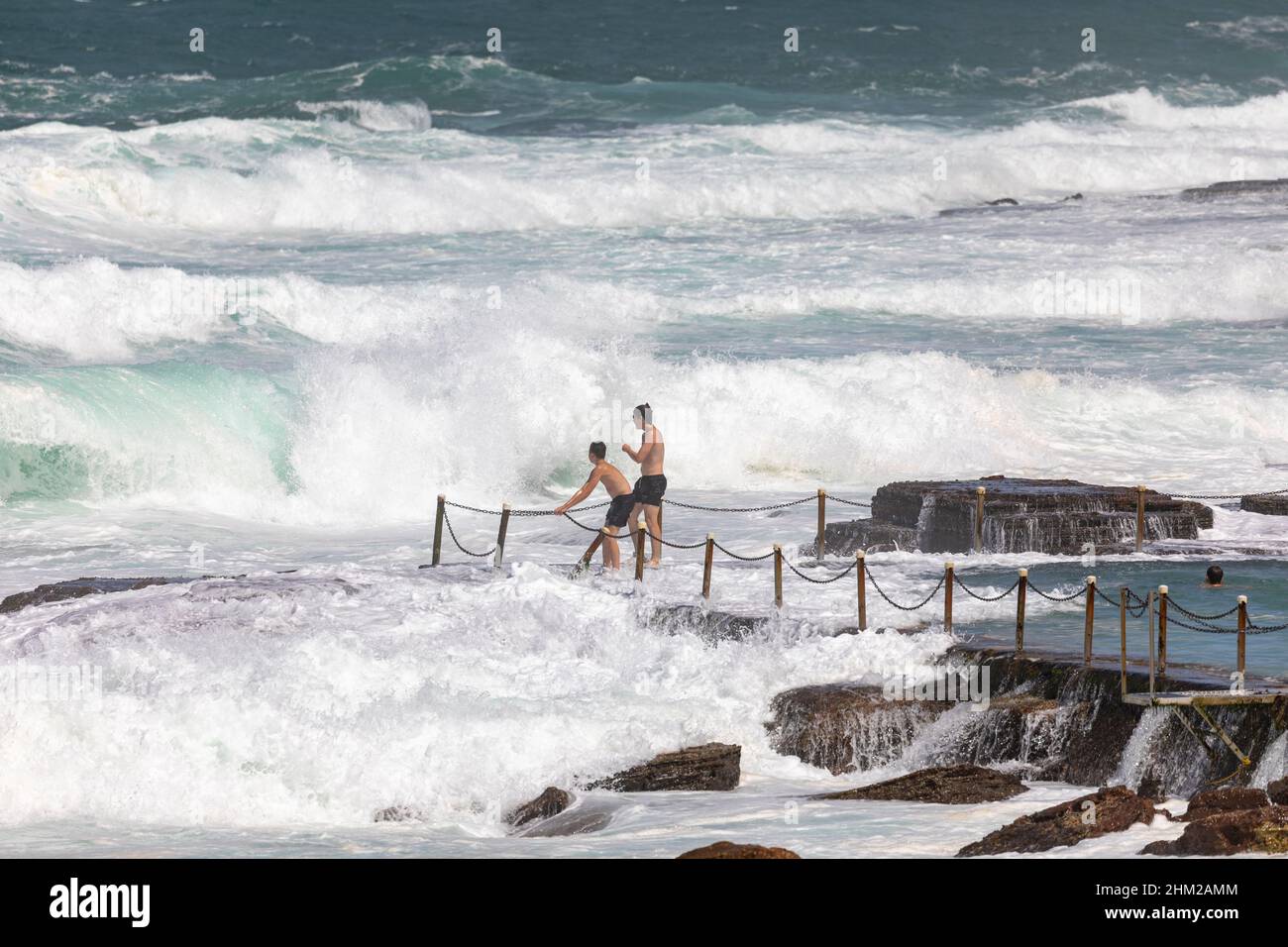 Two australian teenage boys playing and having fun in the large surf at ...