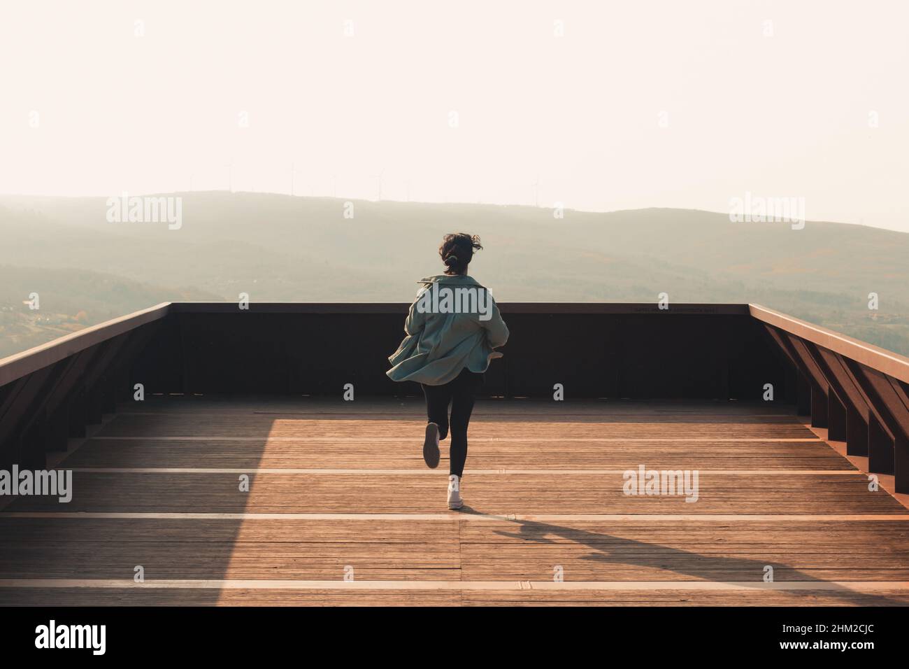 Woman running to the horizon in a balcony during a colorful sunset ...