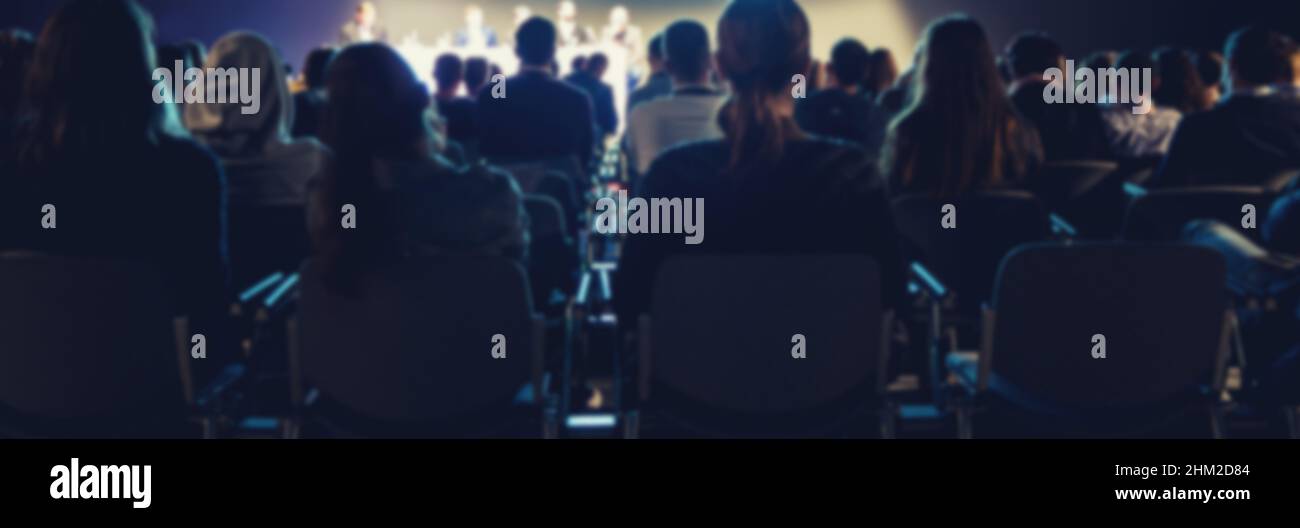 Speakers on the stage with Rear view of Audience in the conference hall ...