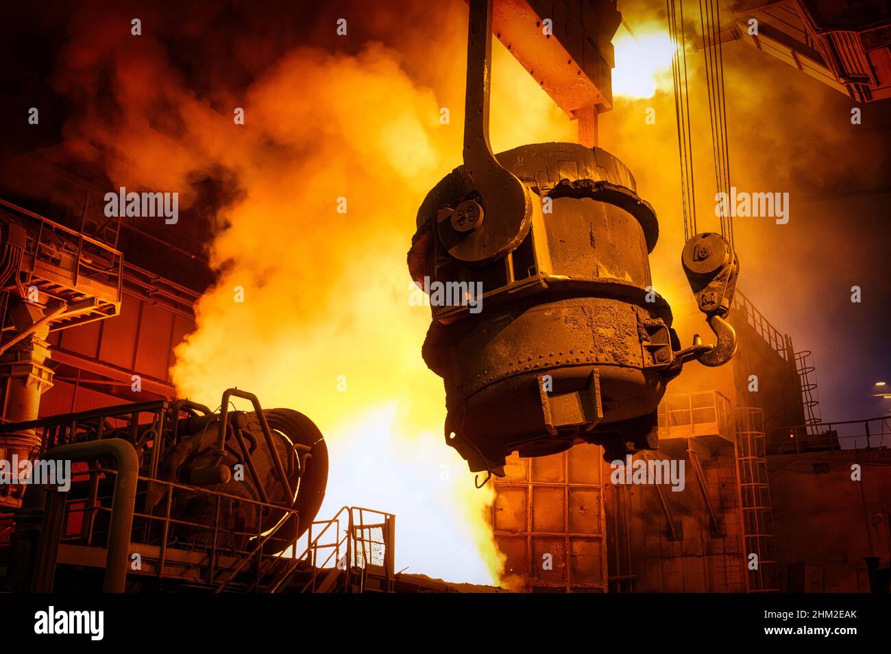 A metallurgical ladle filled with molten metal bucket is suspended on a ...