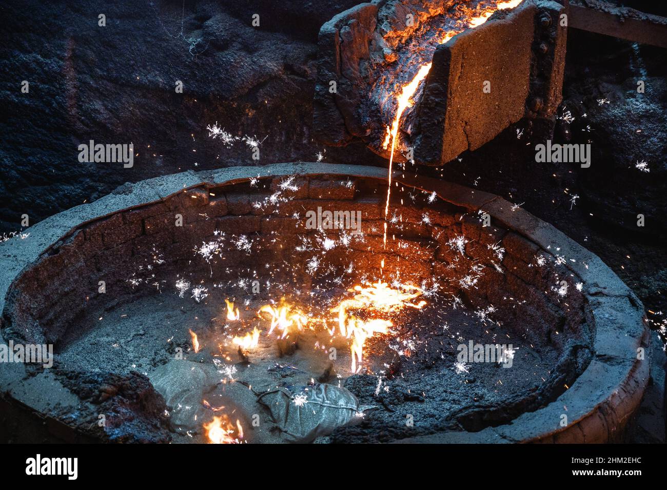 Liquid cast iron is poured into the ladle in a thin stream. Lots of ...