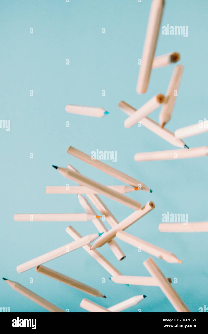 Pencils falling over a pastel blue background, school concept, copy ...