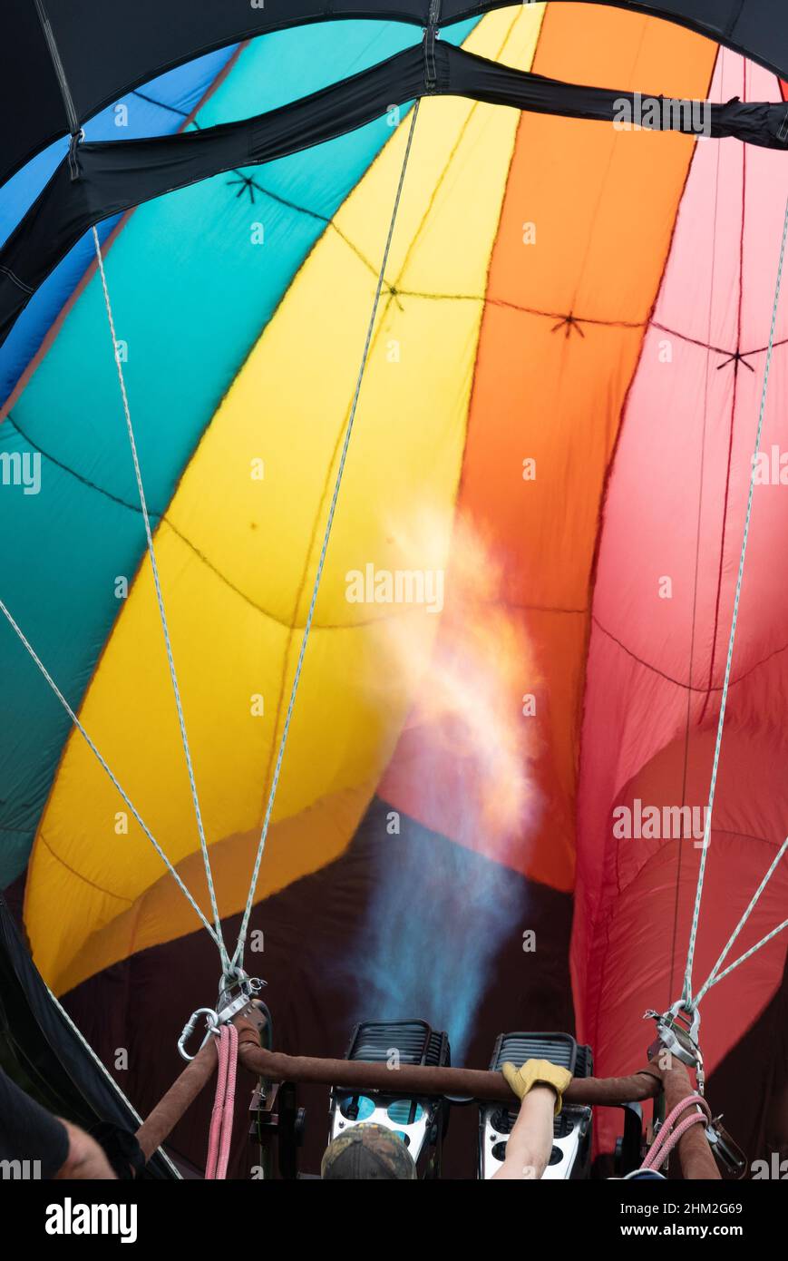 Pilot and assistant inflating a hot air balloon with a burner burning ...