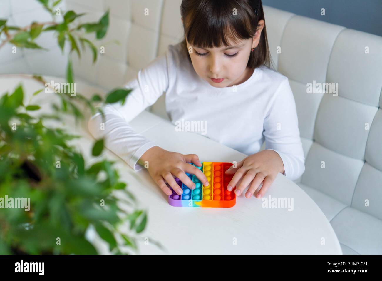 Baby girl playing with rainbow pop it fidget. The concept of mental ...
