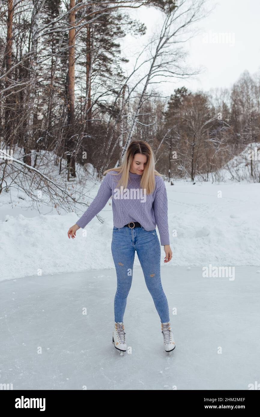Lovely young woman riding ice skates on the ice rink. Girl skating on ...