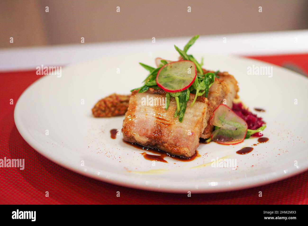 Sliced crispy roasted pork belly with sauce on white plate at asia ...