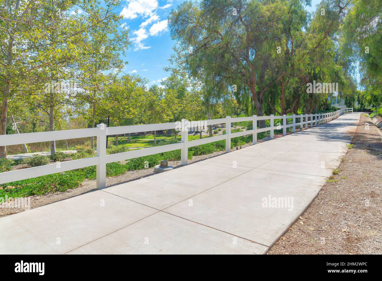 Small concrete path with white fence barrier and trees at Ladera Ranch ...