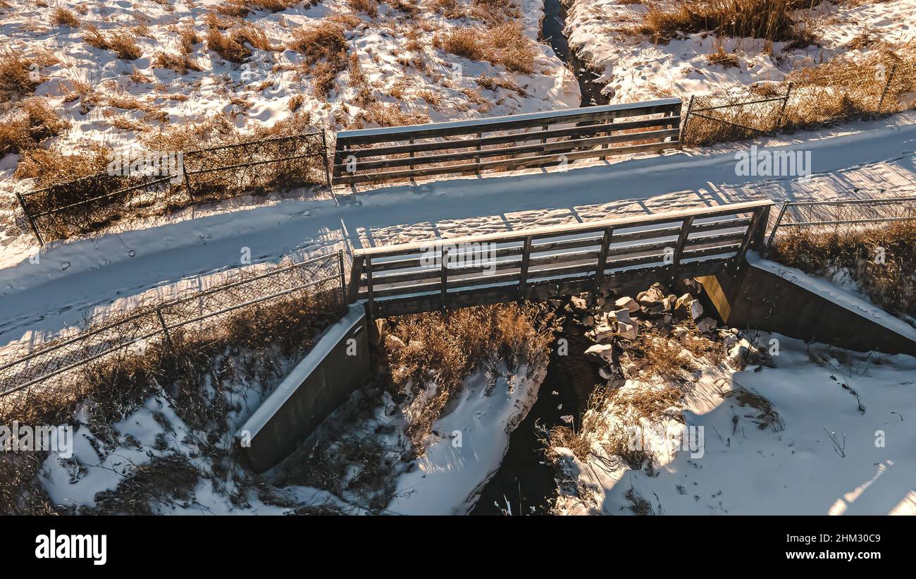 Public walking path in winter with snow and tracks. Sun sets over the ...