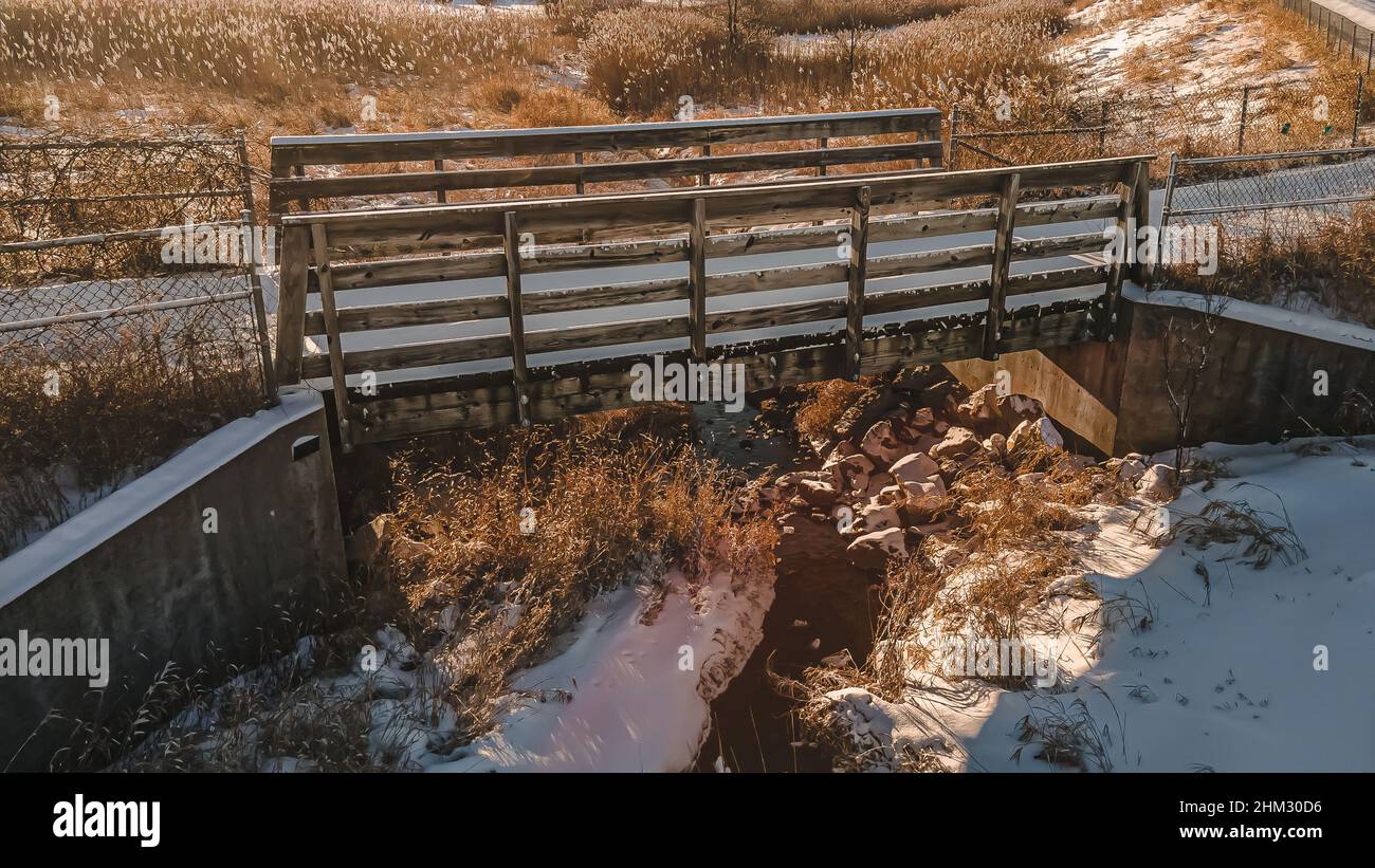 Public walking path in winter with snow and tracks. Sun sets over the ...