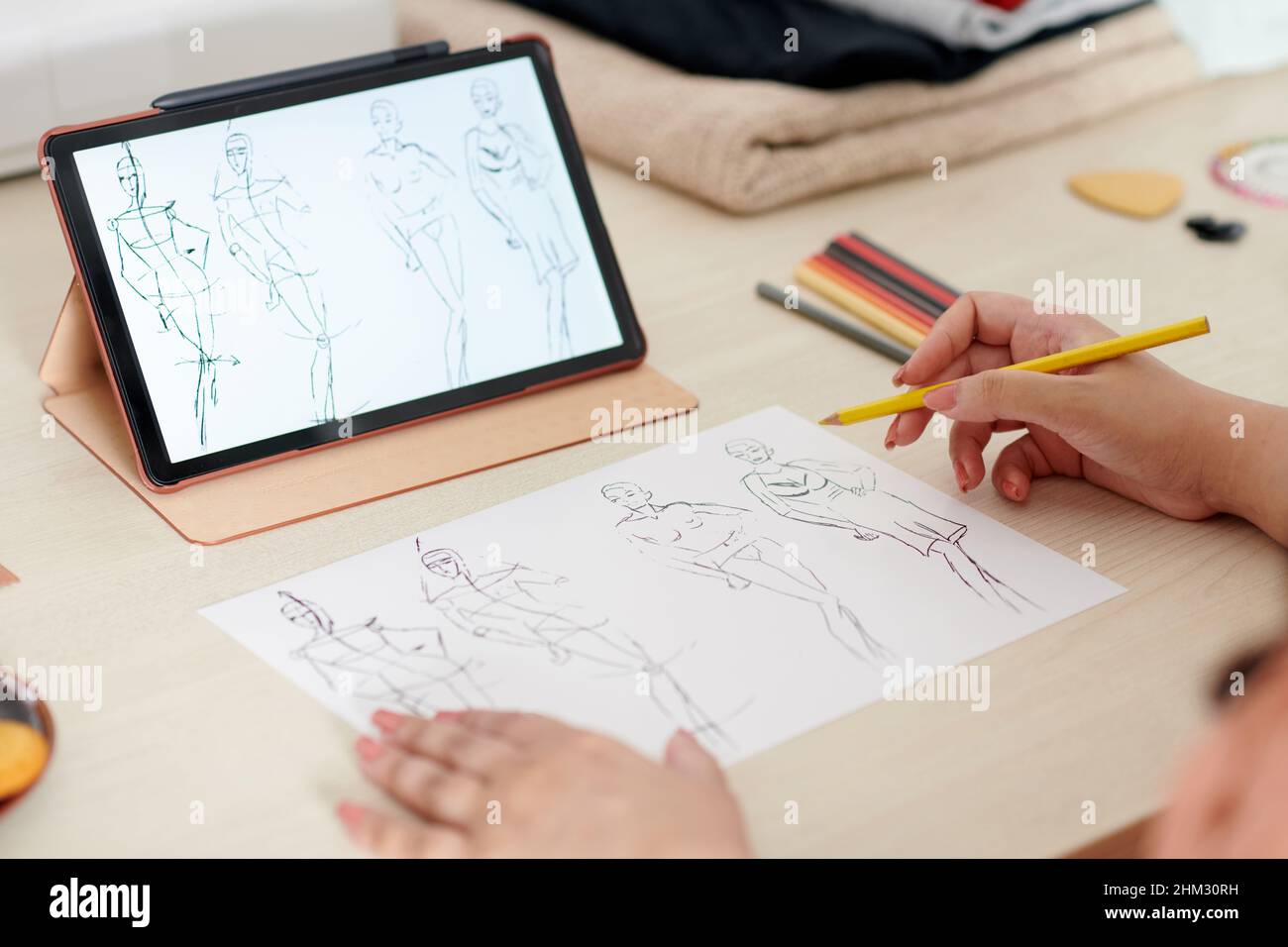 Designer watching tutorial how to draw fashion sketches on tablet ...