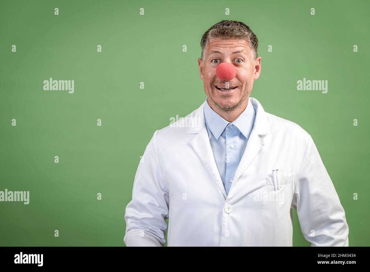 Scientist with white coat has red clown nose on and stands in front of ...
