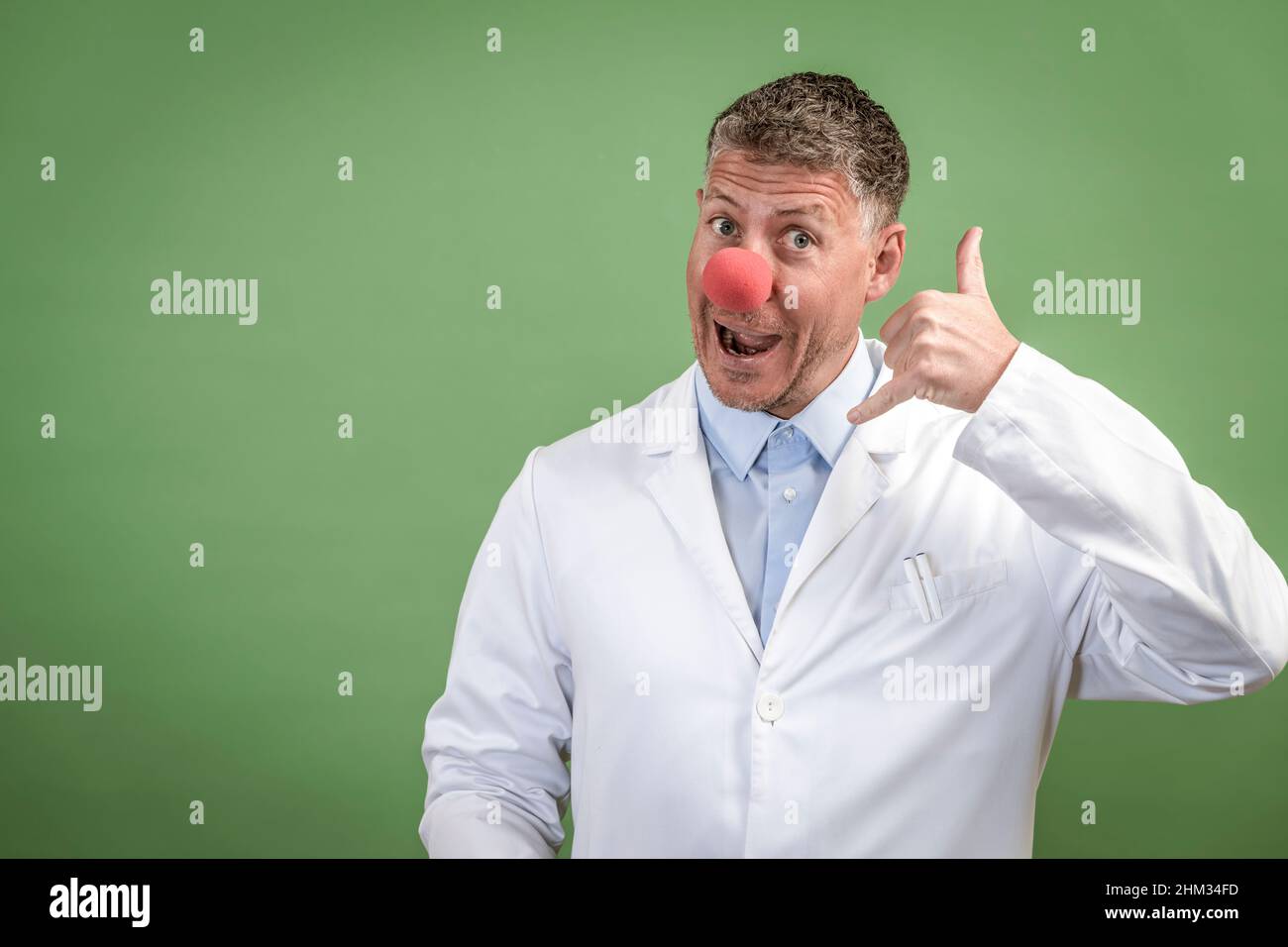 Scientist with white coat has red clown nose on and stands in front of ...
