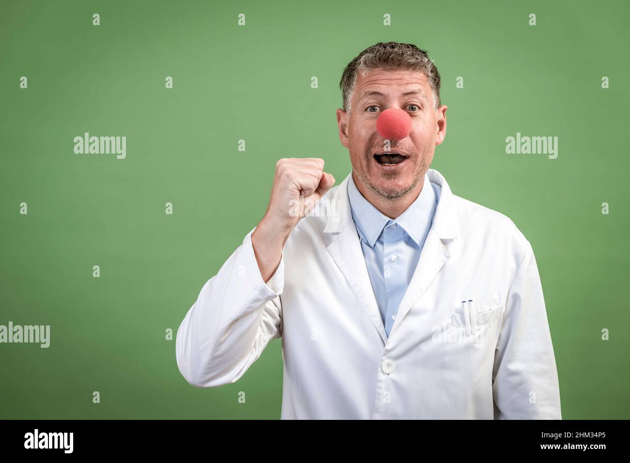 Scientist with white coat has red clown nose on and stands in front of ...