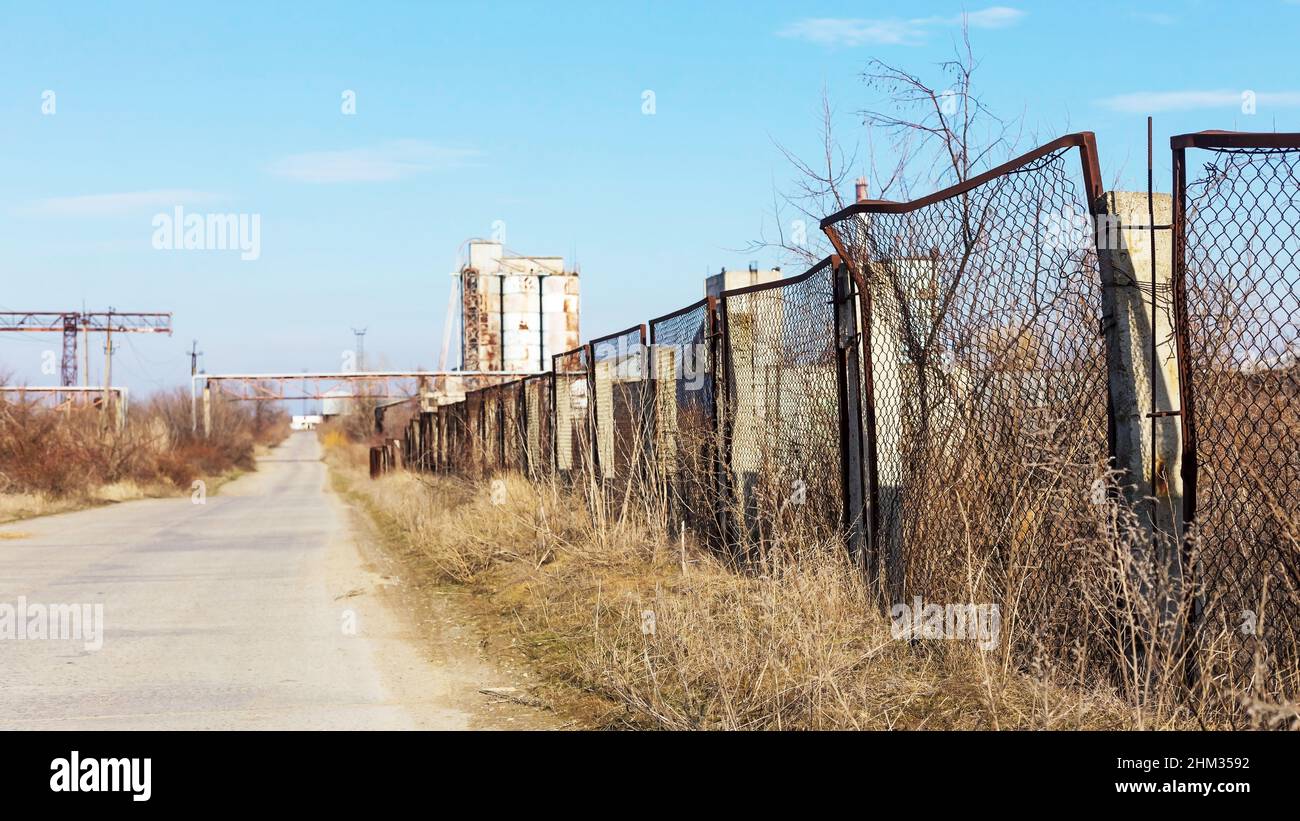 Rusty metal fence along a road receding into the distance to the old ...