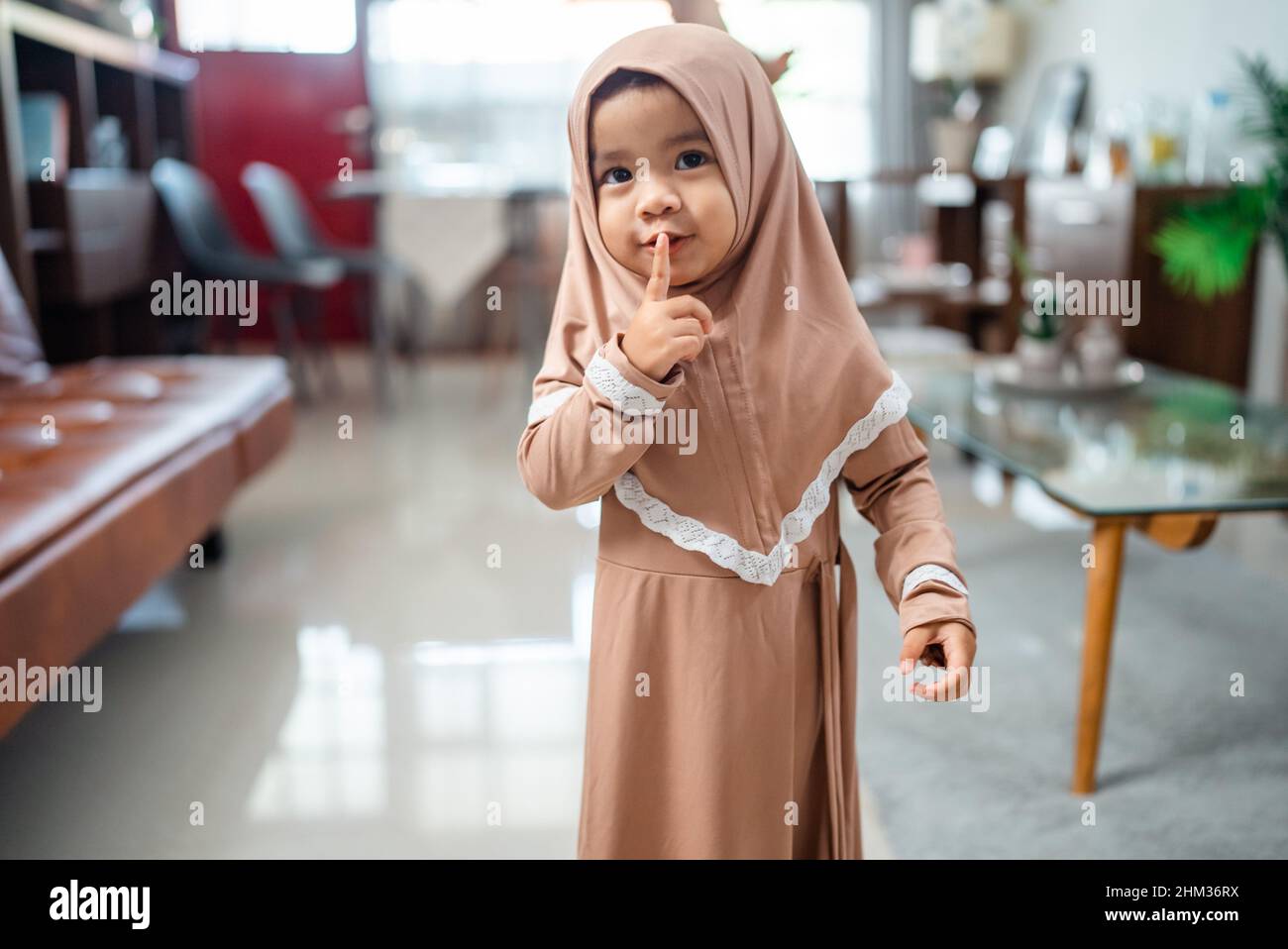 kid with hushing gesture wearing muslim headscarf at home Stock Photo ...