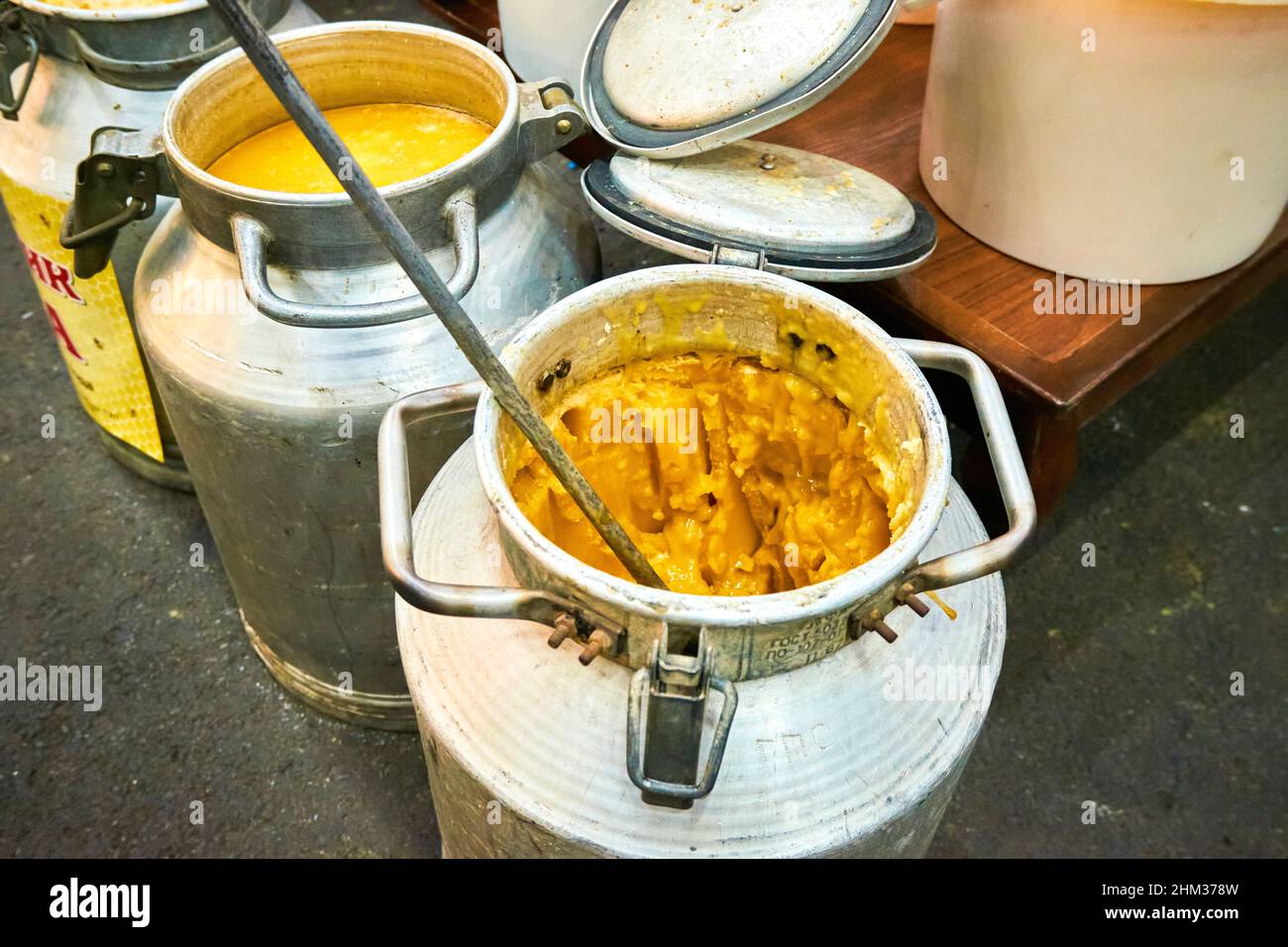 Varieties of honey, stored in traditional metal milk bucket containers ...