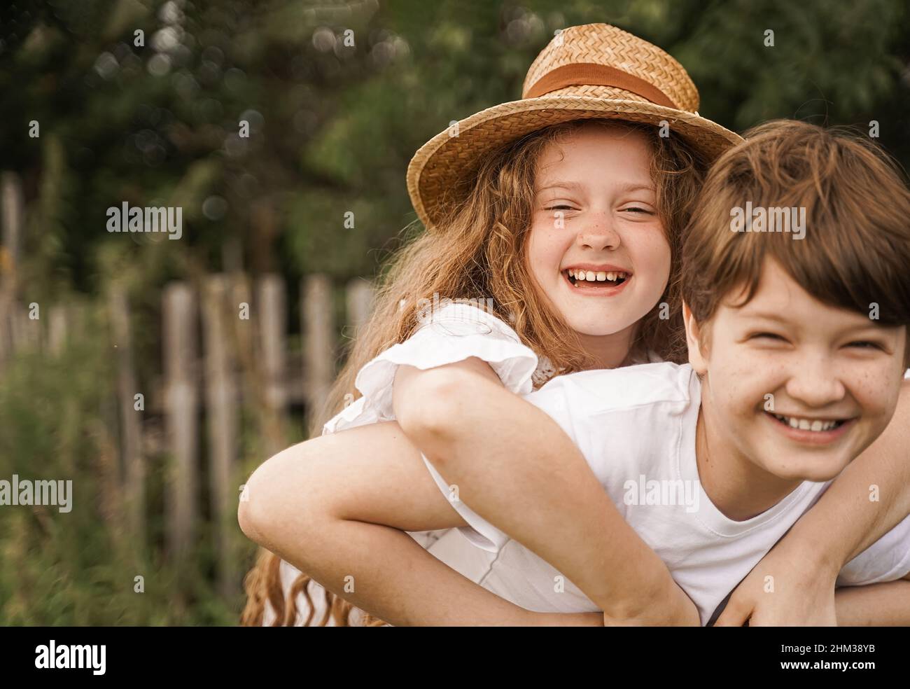 Happy children with piggyback riding in sunset light. Girls laugh ...