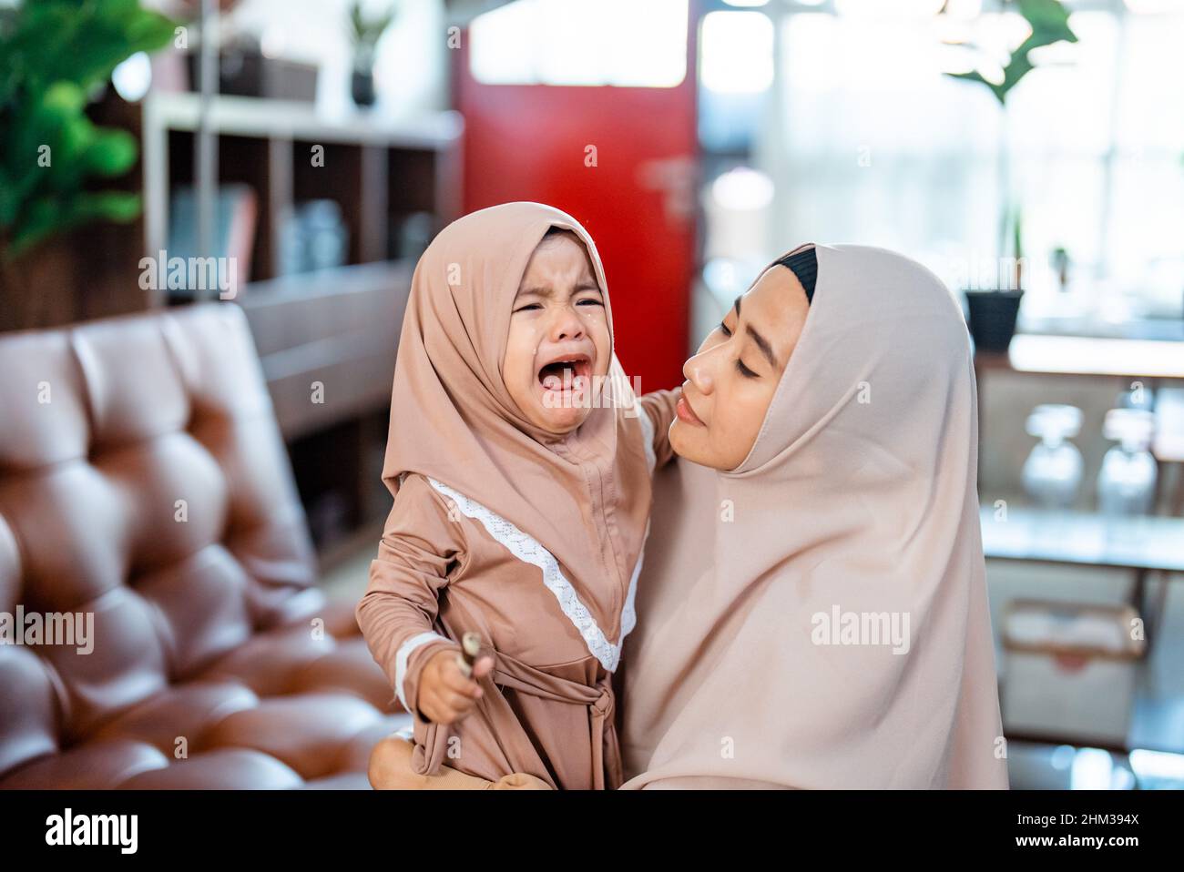 muslim Mother with hijab scarf comforting her crying little girl Stock ...