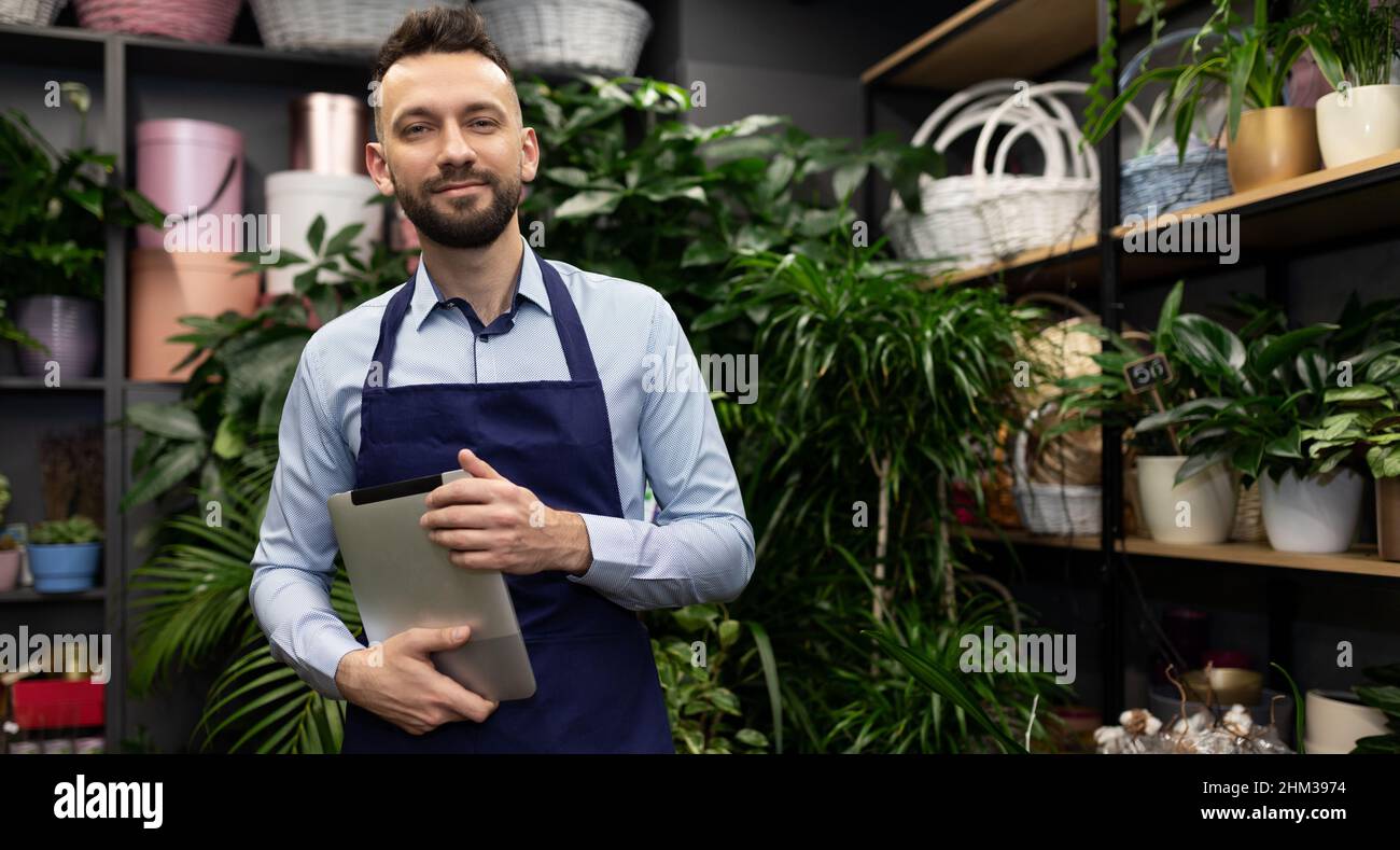 the owner of the garden center with a tablet in his hands next to the ...