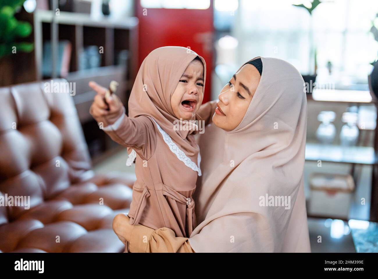 muslim Mother with hijab scarf comforting her crying little girl Stock ...