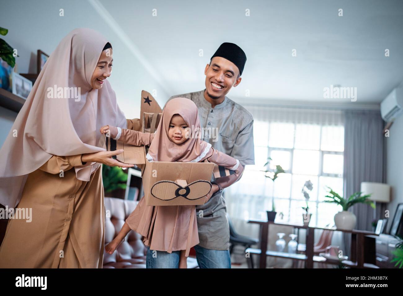 muslim parent playing cardboard airplane with their adorable young ...