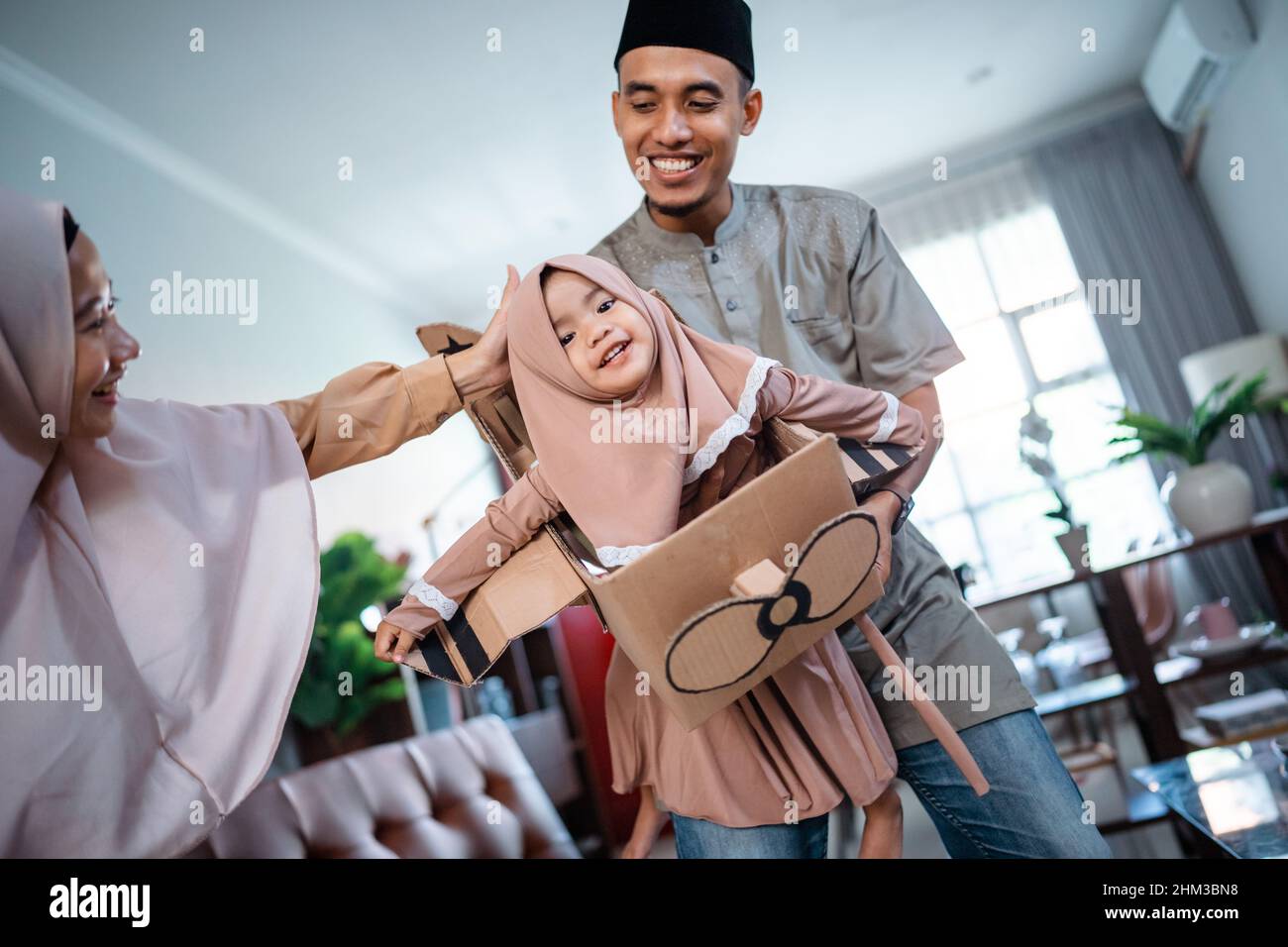muslim parent playing cardboard airplane with their adorable young ...
