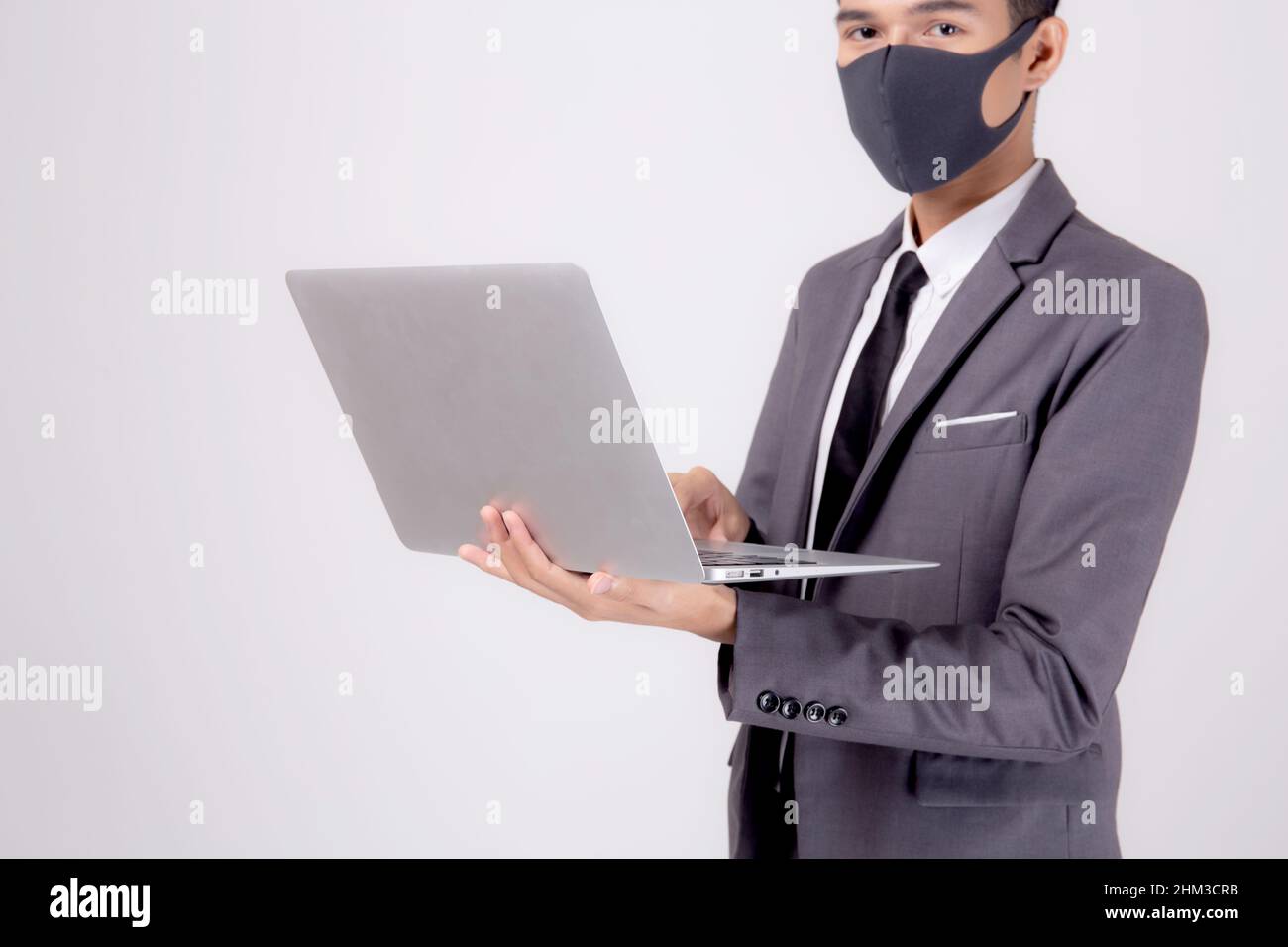 Young asian business man in face mask using laptop computer isolated on ...