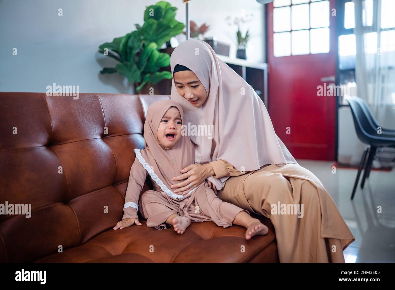 muslim Mother with hijab scarf comforting her crying little girl Stock ...