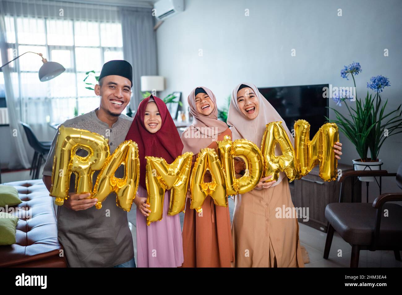 family wearing muslim traditional clothes holding a text of ramadan ...