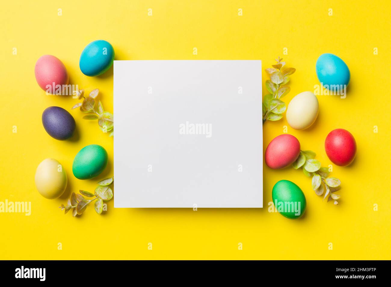 round frame multicolored Easter eggs with white blank paper on a brown ...