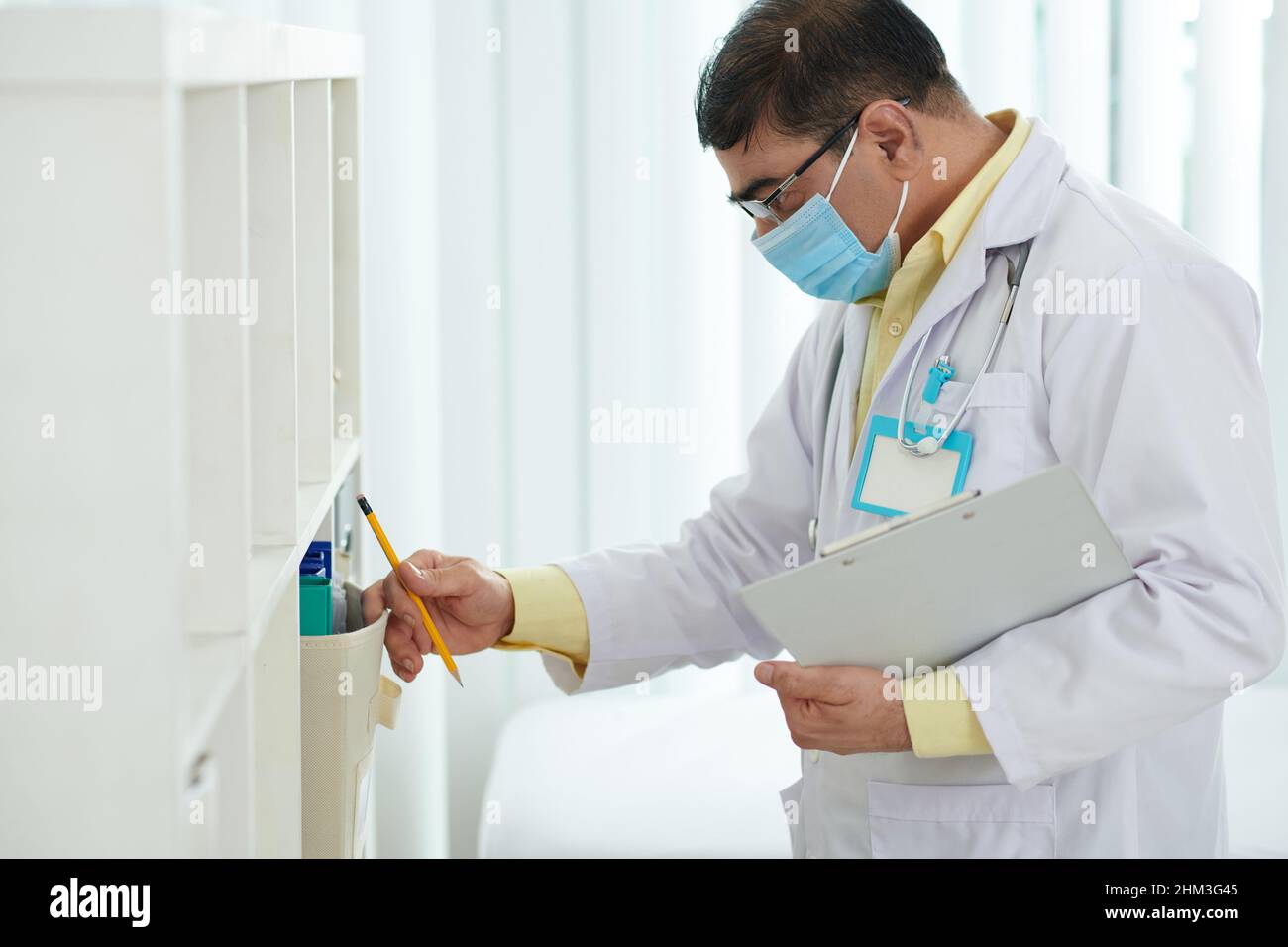 General practitioner in medical mask searching for certain document on ...
