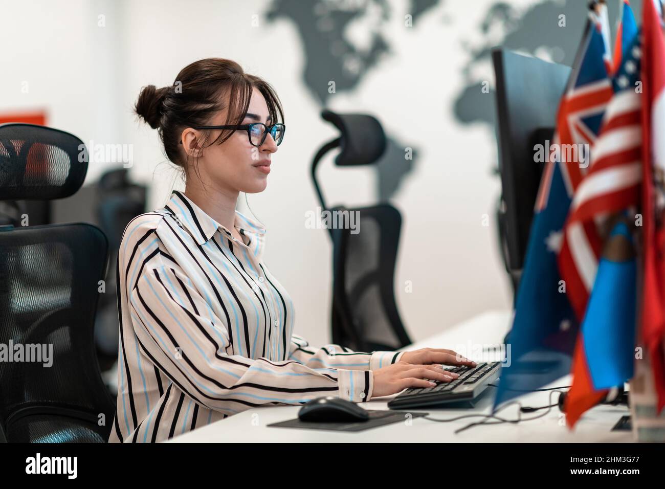 Casual business woman working on desktop computer in modern open plan ...