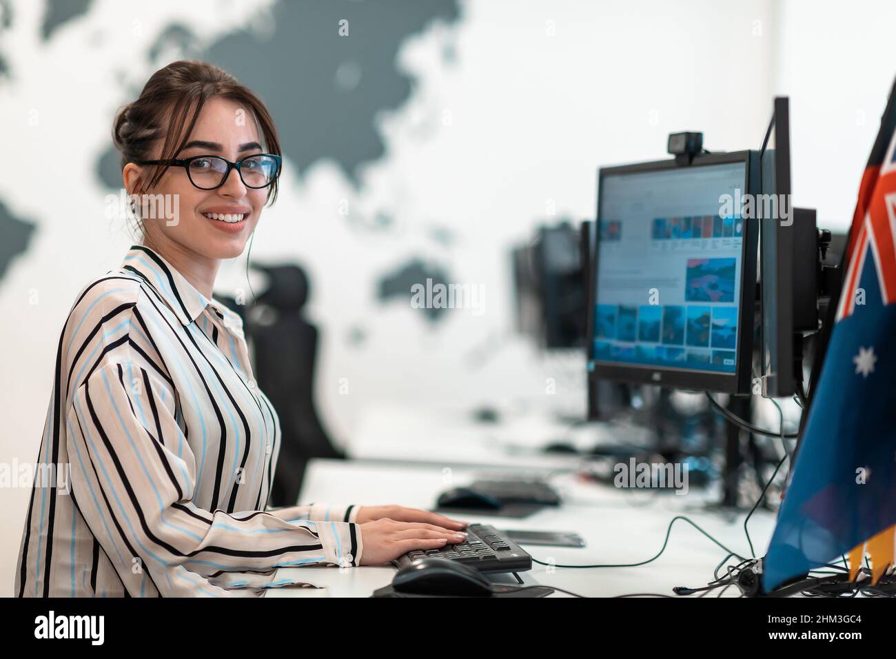 Casual business woman working on desktop computer in modern open plan ...