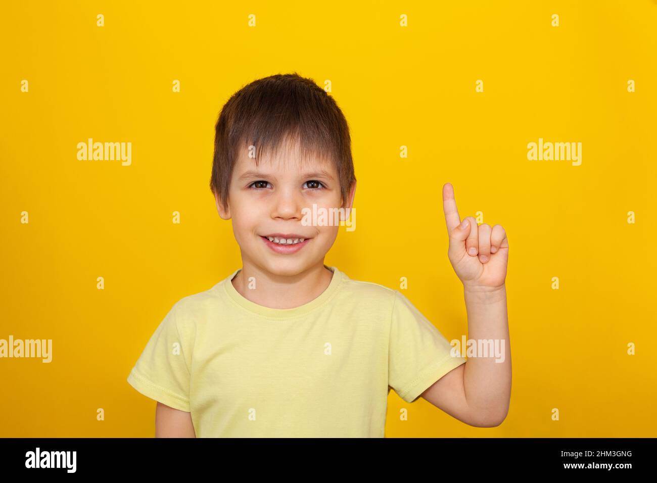 Portrait of smiling little boy with finger pointed up. Kid isolated on ...