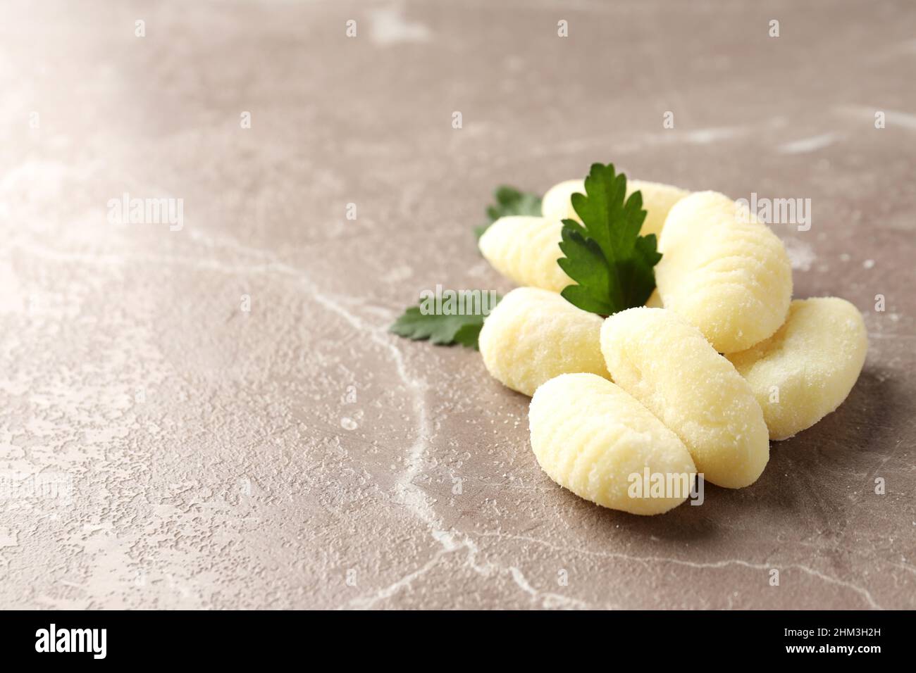 Raw potato gnocchi on gray textured background, space for text Stock ...