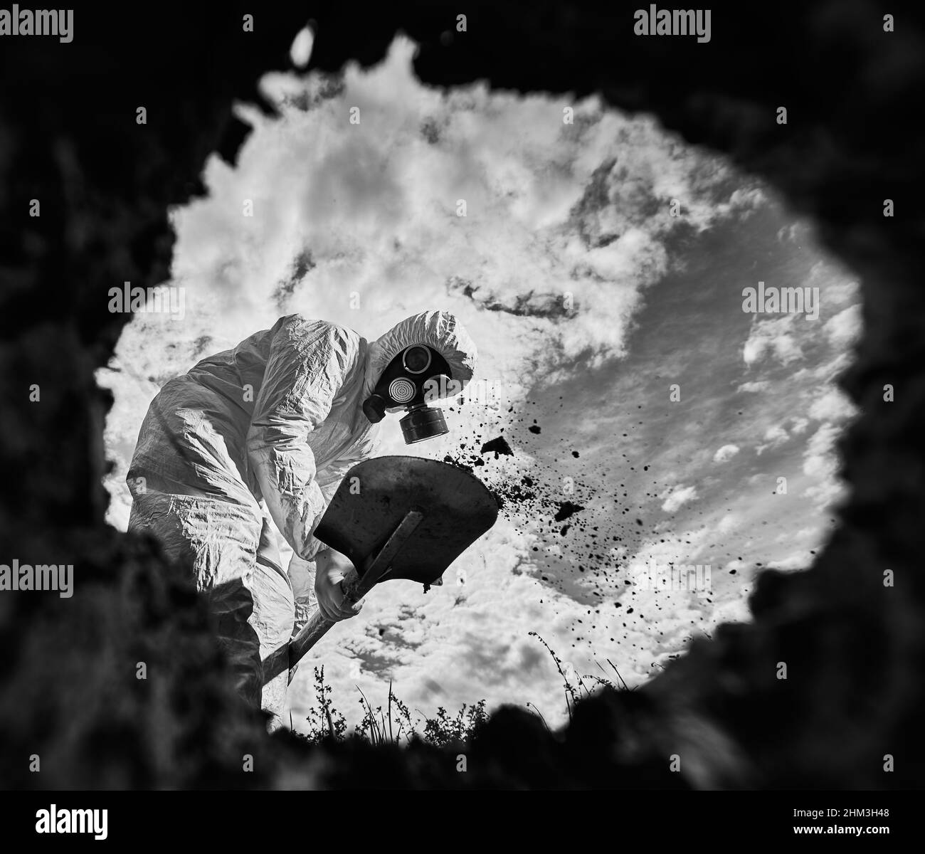 Black and white filter view of male scientist in gas mask using shovel ...