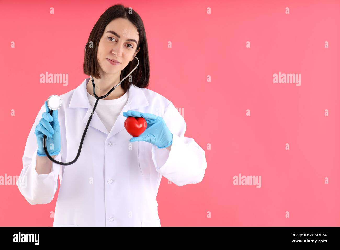 Female trainee doctor with heart on pink background Stock Photo - Alamy