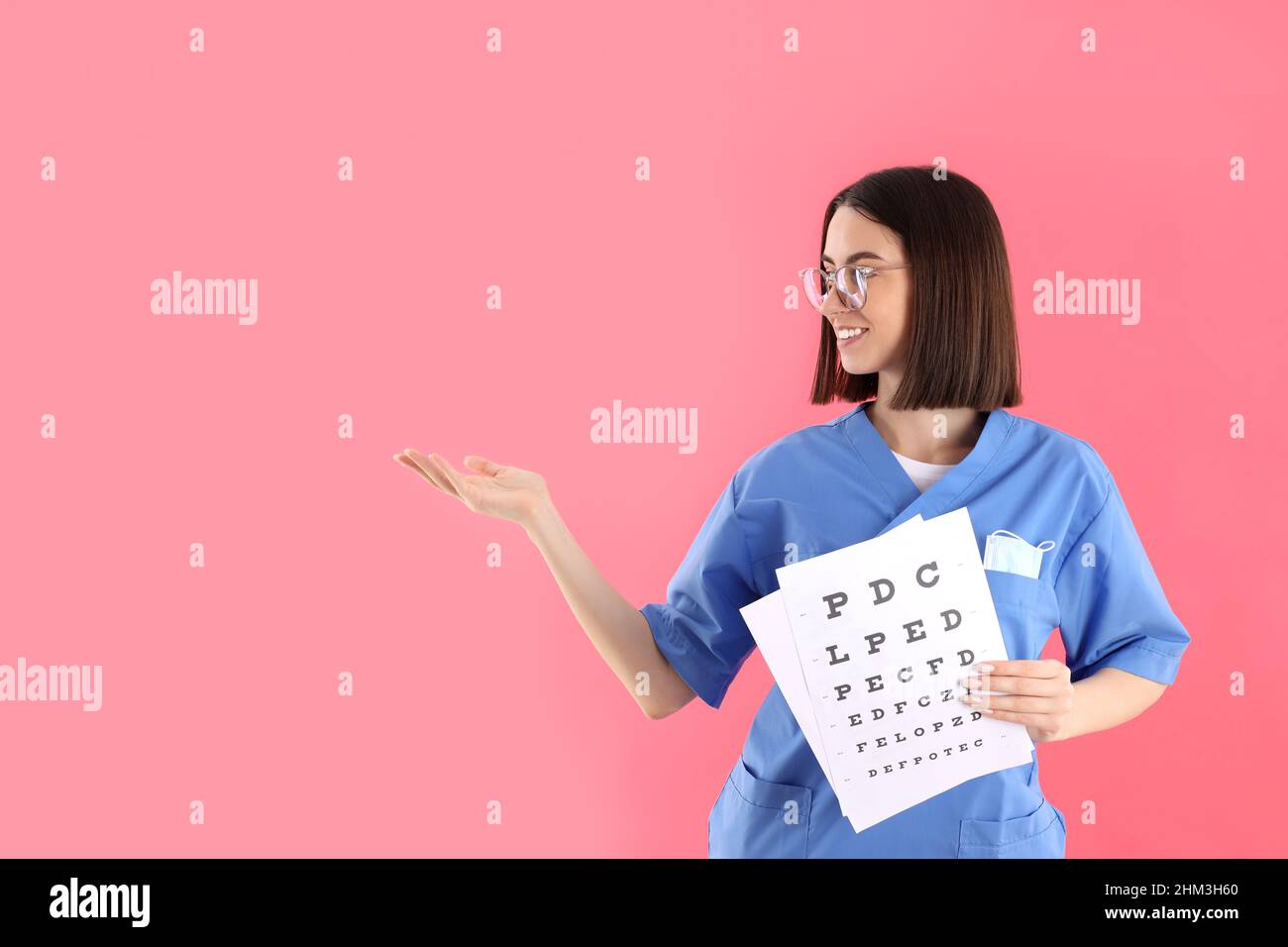 Female trainee nurse with vision test on pink background Stock Photo ...