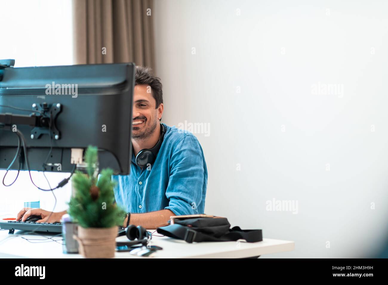 Casual man working on desktop computer in modern open plan startup ...