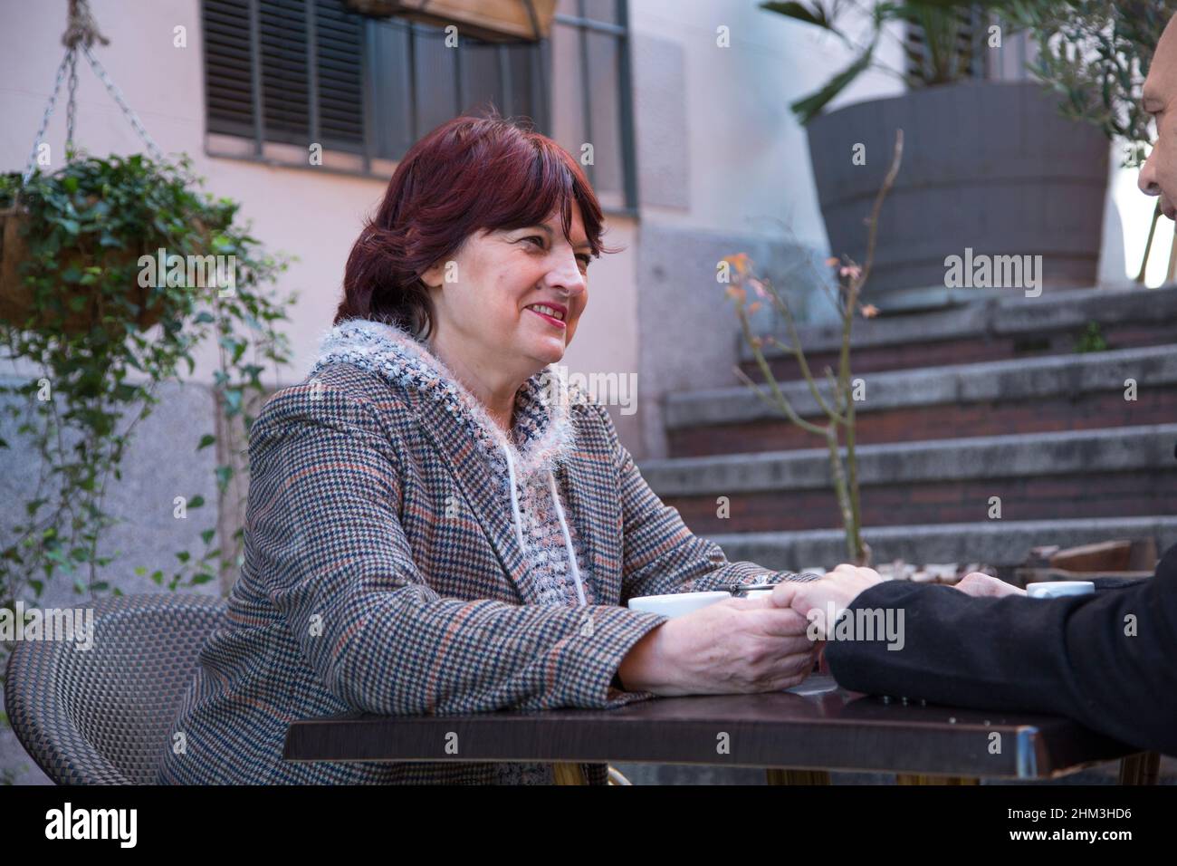 senior woman grabbing the hands of another person at a restaurant table ...