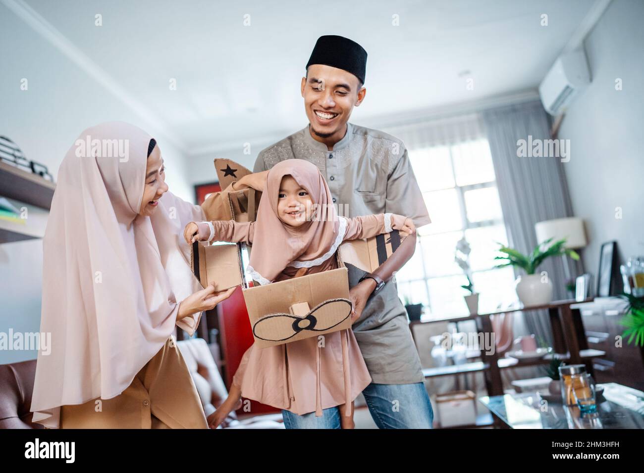 muslim parent playing cardboard airplane with their adorable young ...