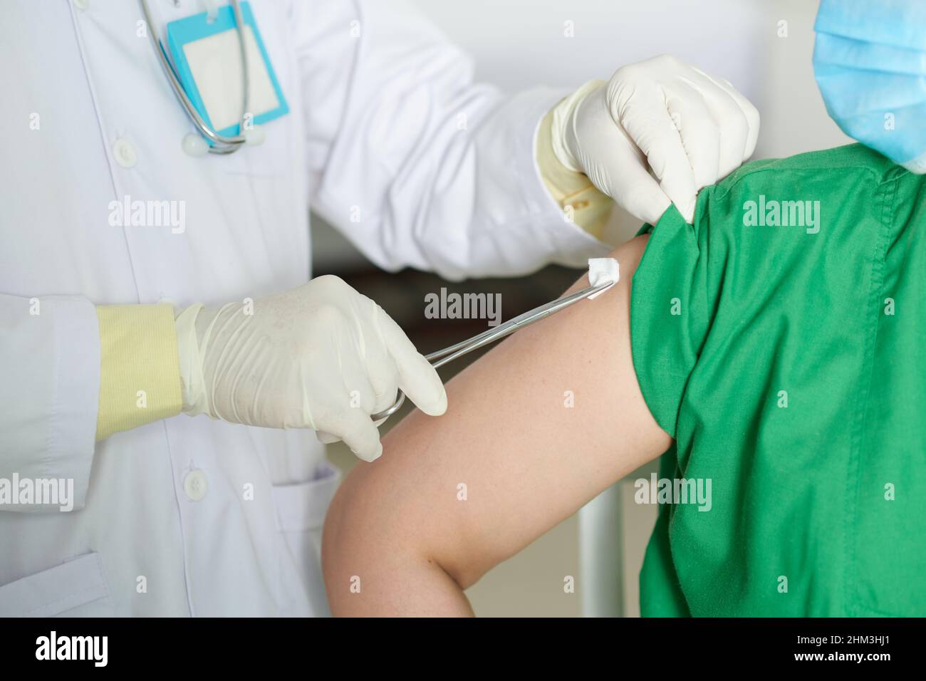Hands of nurse wiping site of injection with cotton pad soaked in ...