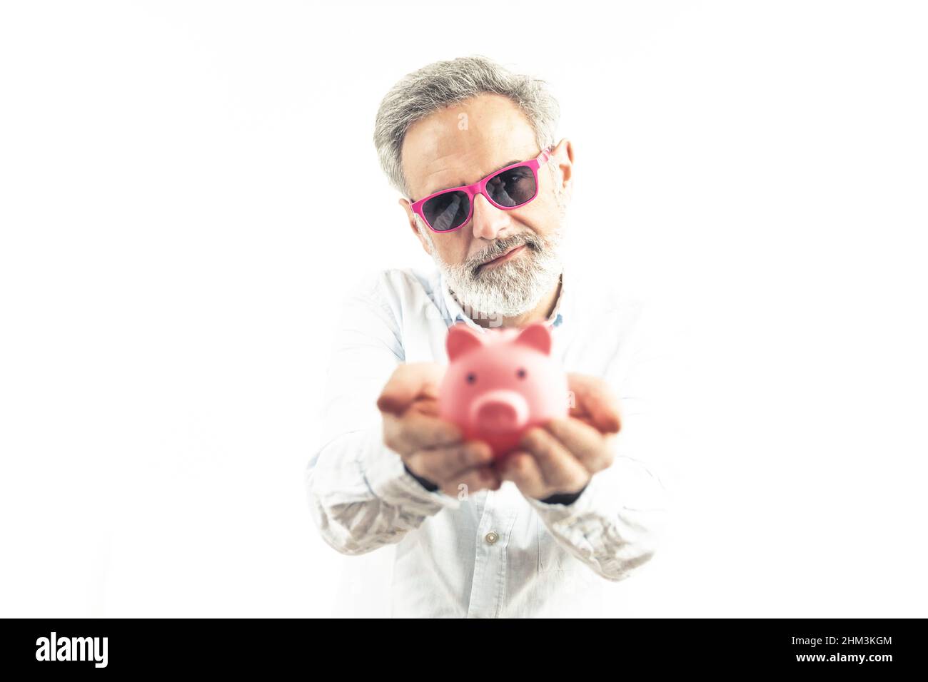 senior man in pink sunglasses holding the piggy bank - savings and ...