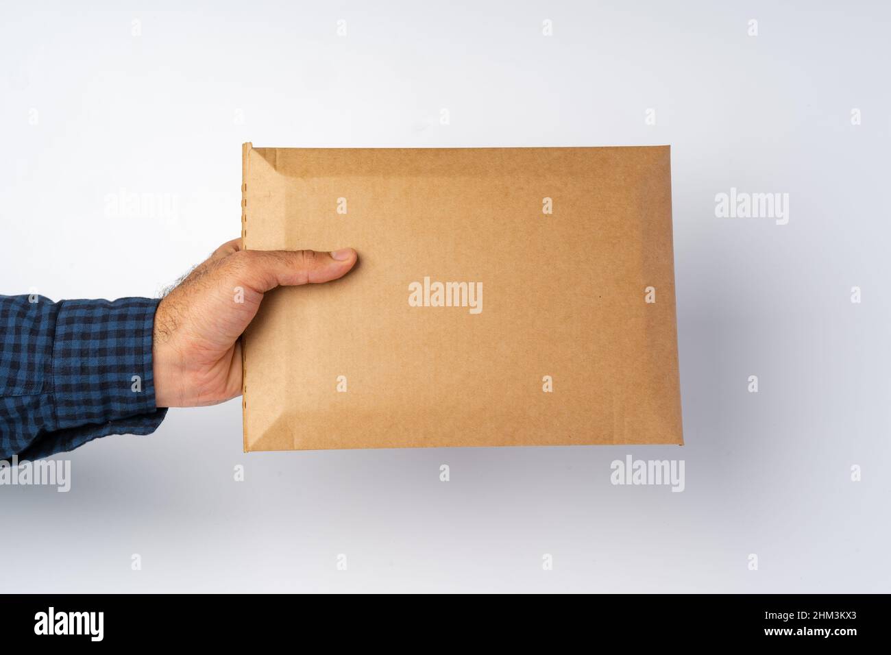 Male hand holding parcel post against white background Stock Photo - Alamy