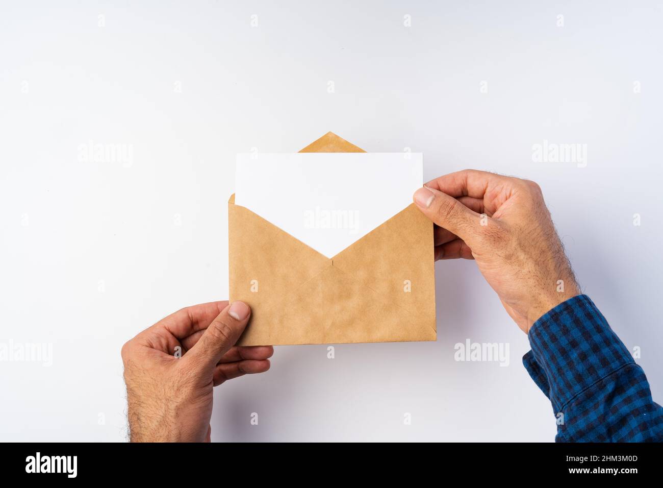 Top view of male hands hold (open) an envelope above white background ...
