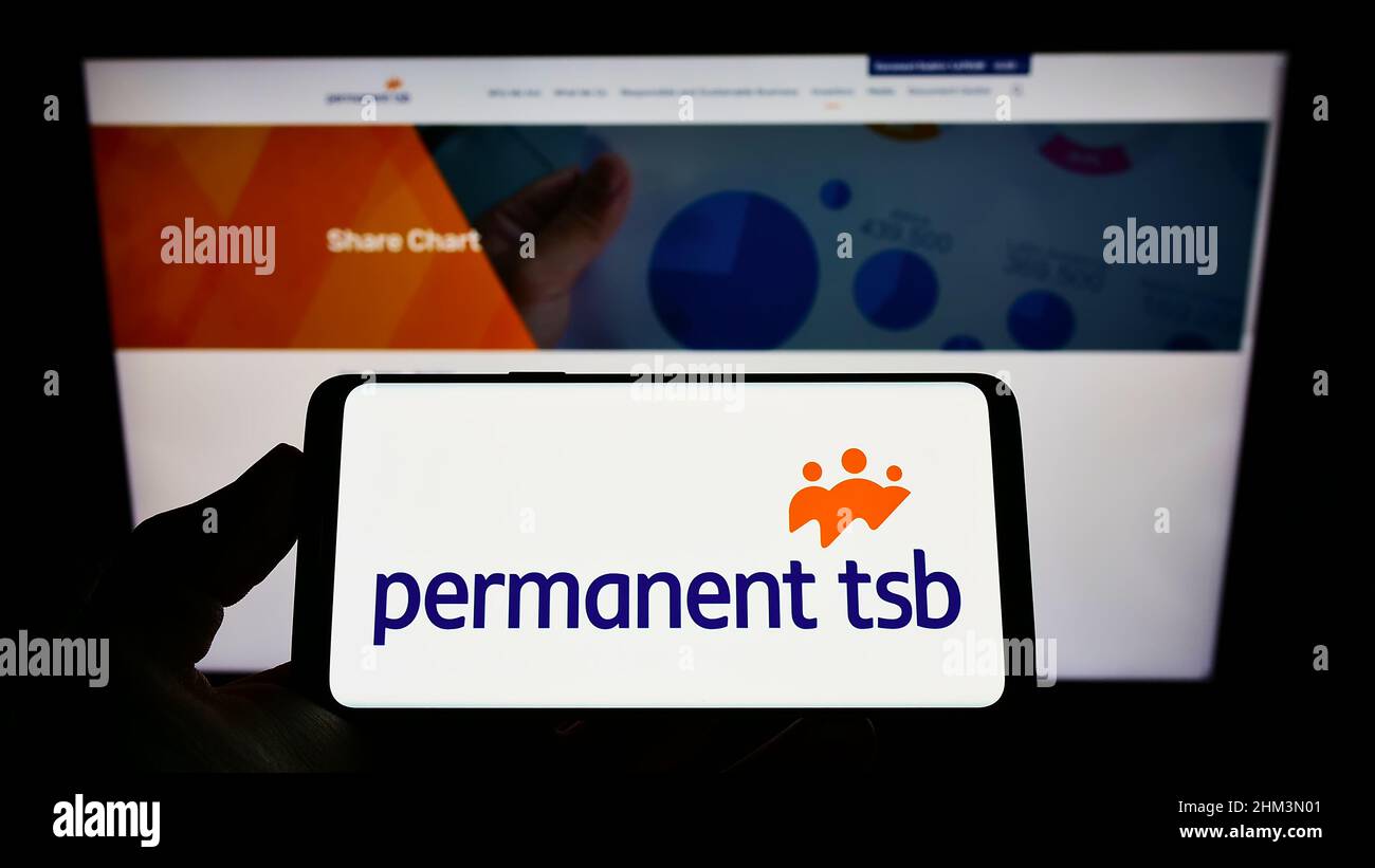 Person holding mobile phone with logo of Irish company Permanent TSB ...